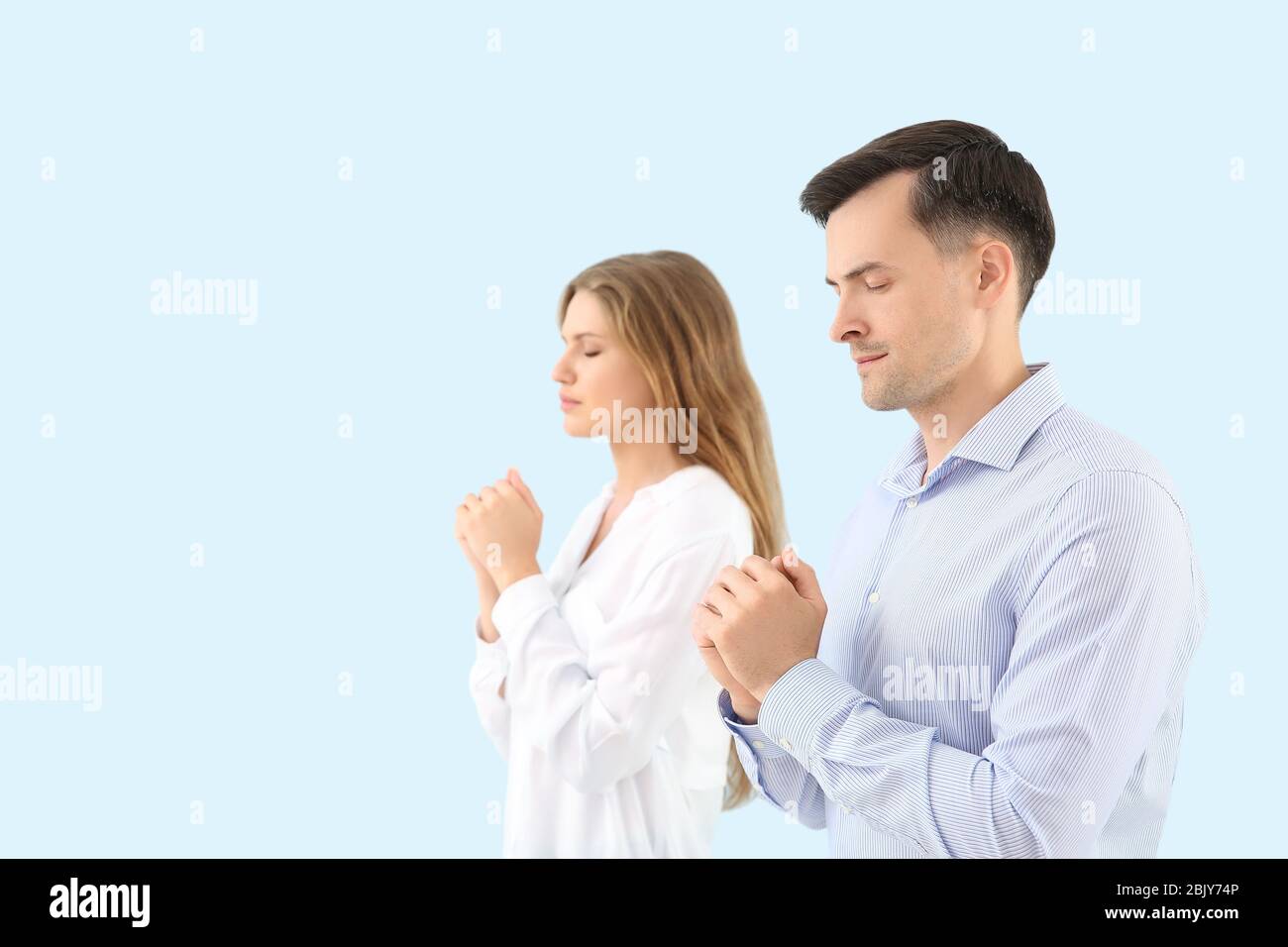 Religious couple praying to God on light color background Stock Photo ...