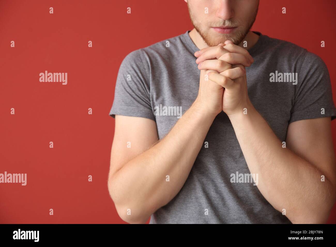 Religious young man praying to God on color background Stock Photo - Alamy