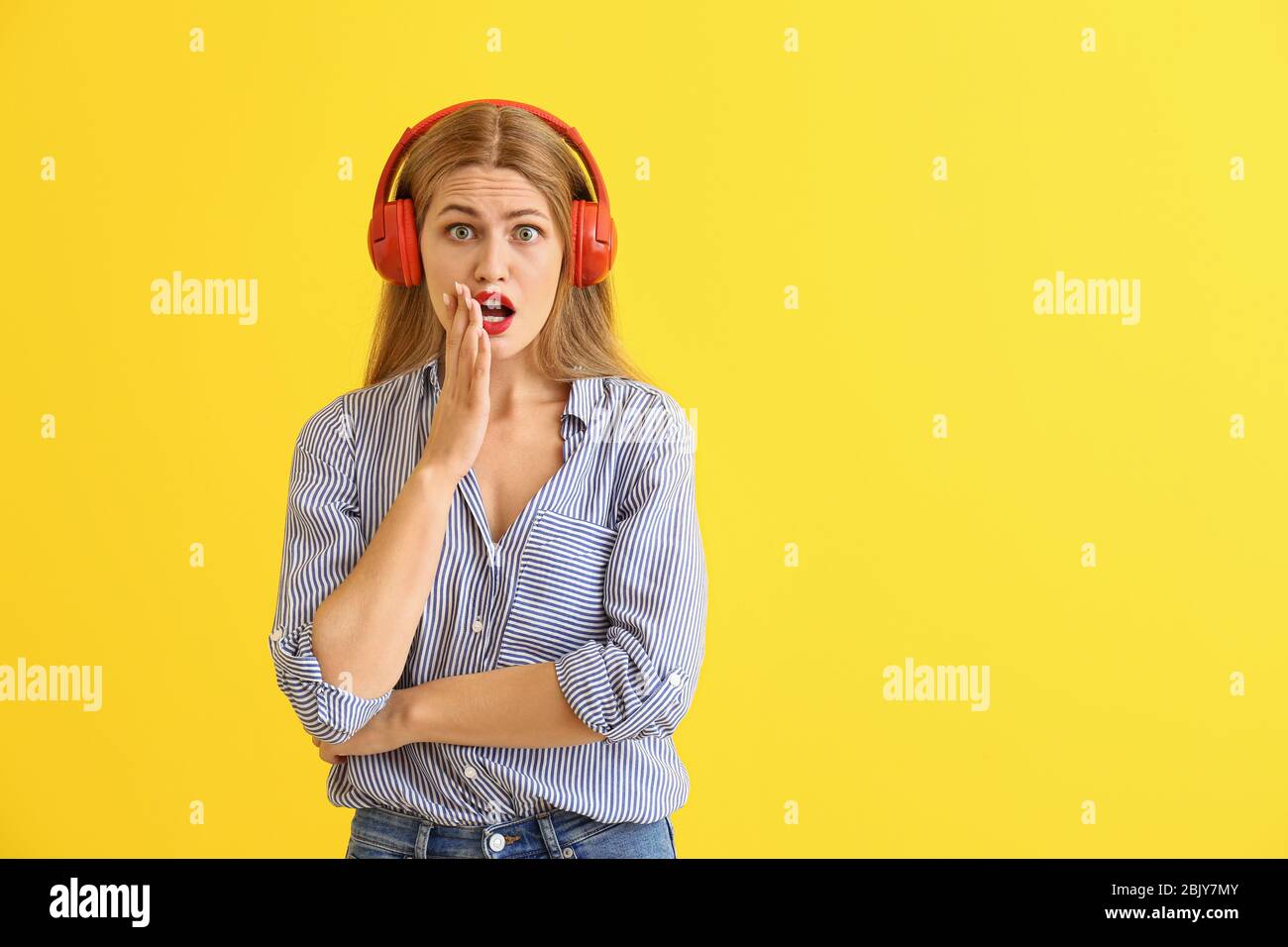 Shocked young woman listening to music on color background Stock Photo ...