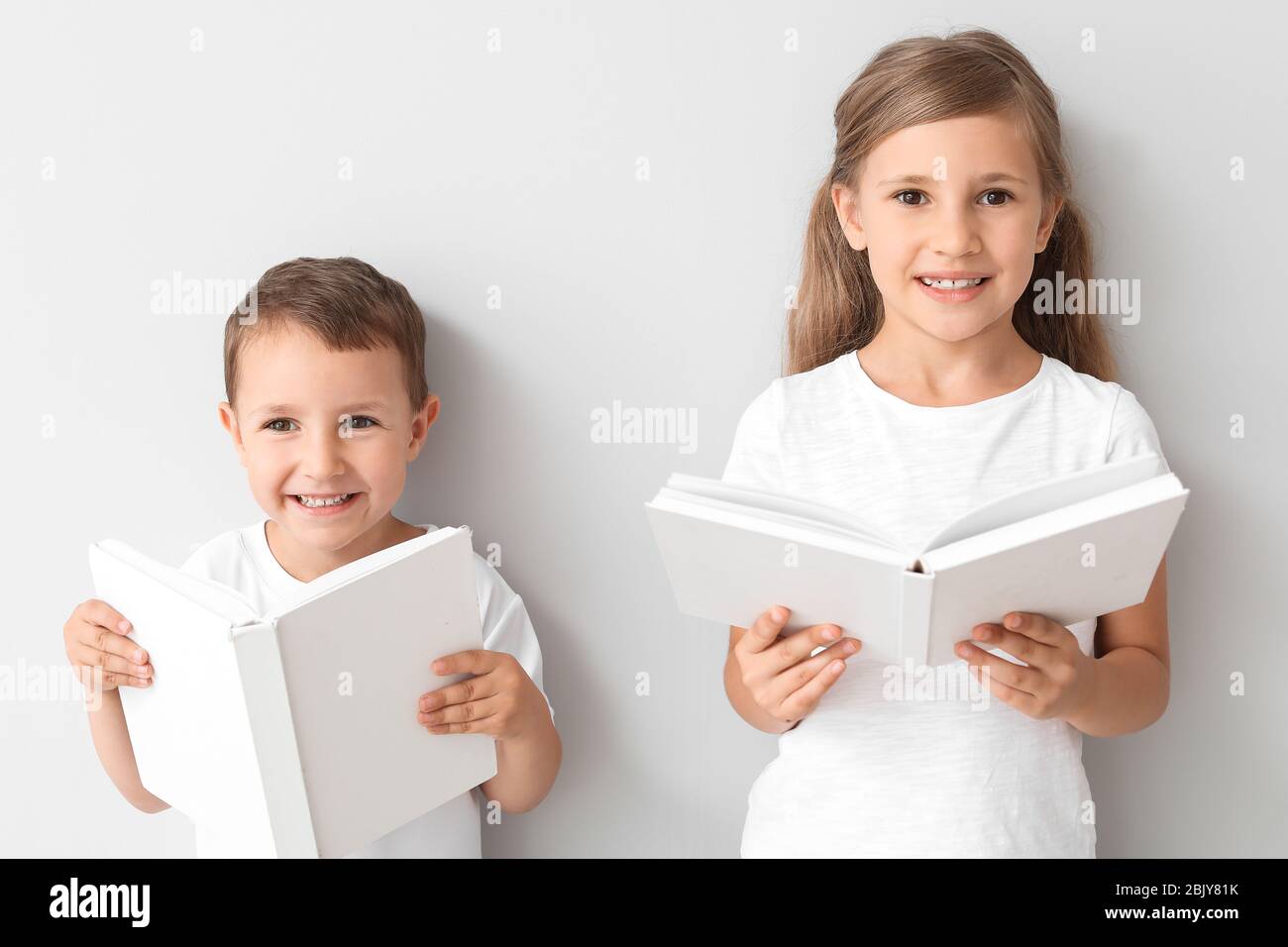 Little children with books on light background Stock Photo - Alamy
