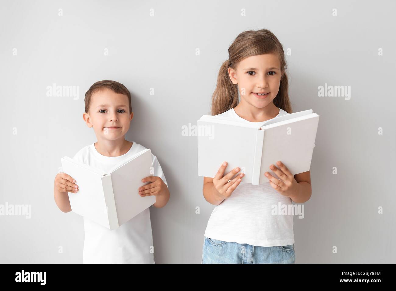 Little children with books on light background Stock Photo - Alamy