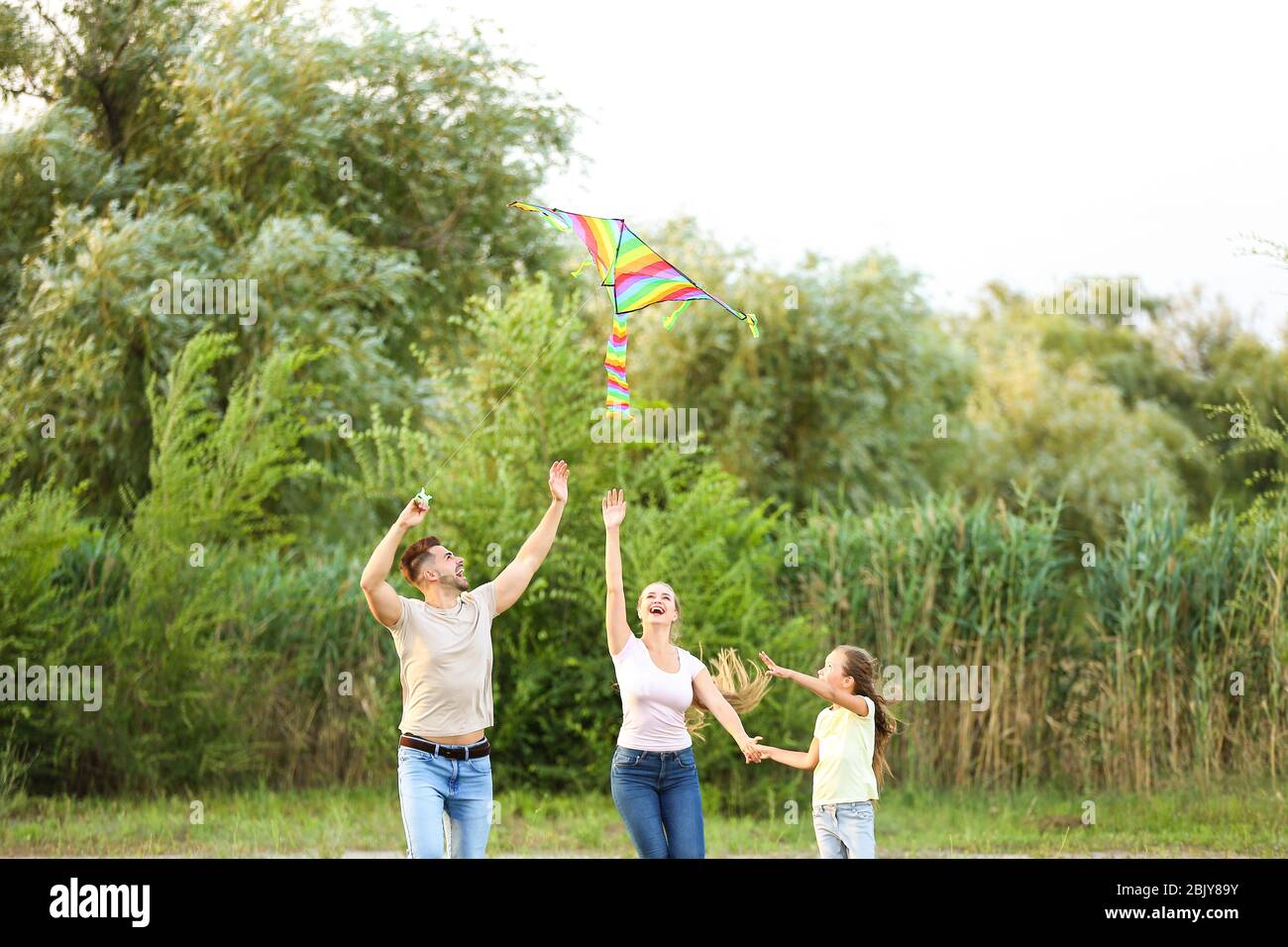 Happy family flying kite outdoors Stock Photo - Alamy