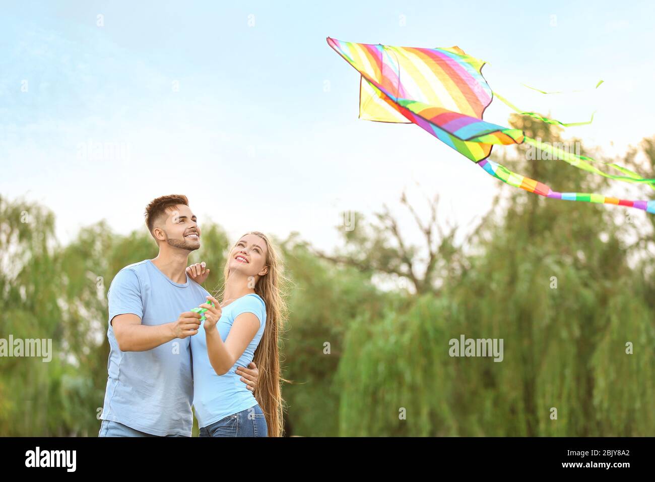 Happy young couple flying kite outdoors Stock Photo - Alamy