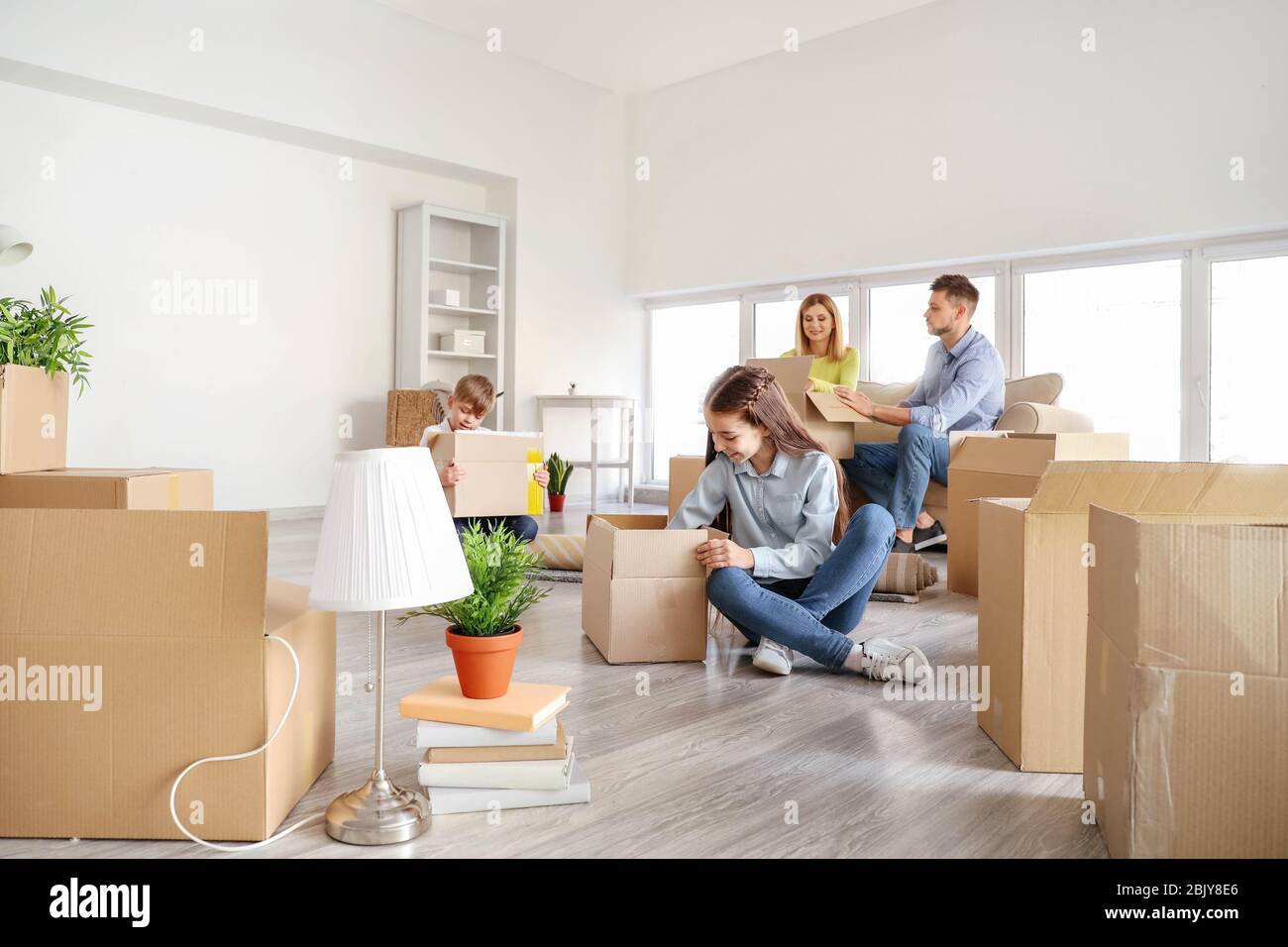 Happy family unpacking belongings in their new house Stock Photo - Alamy