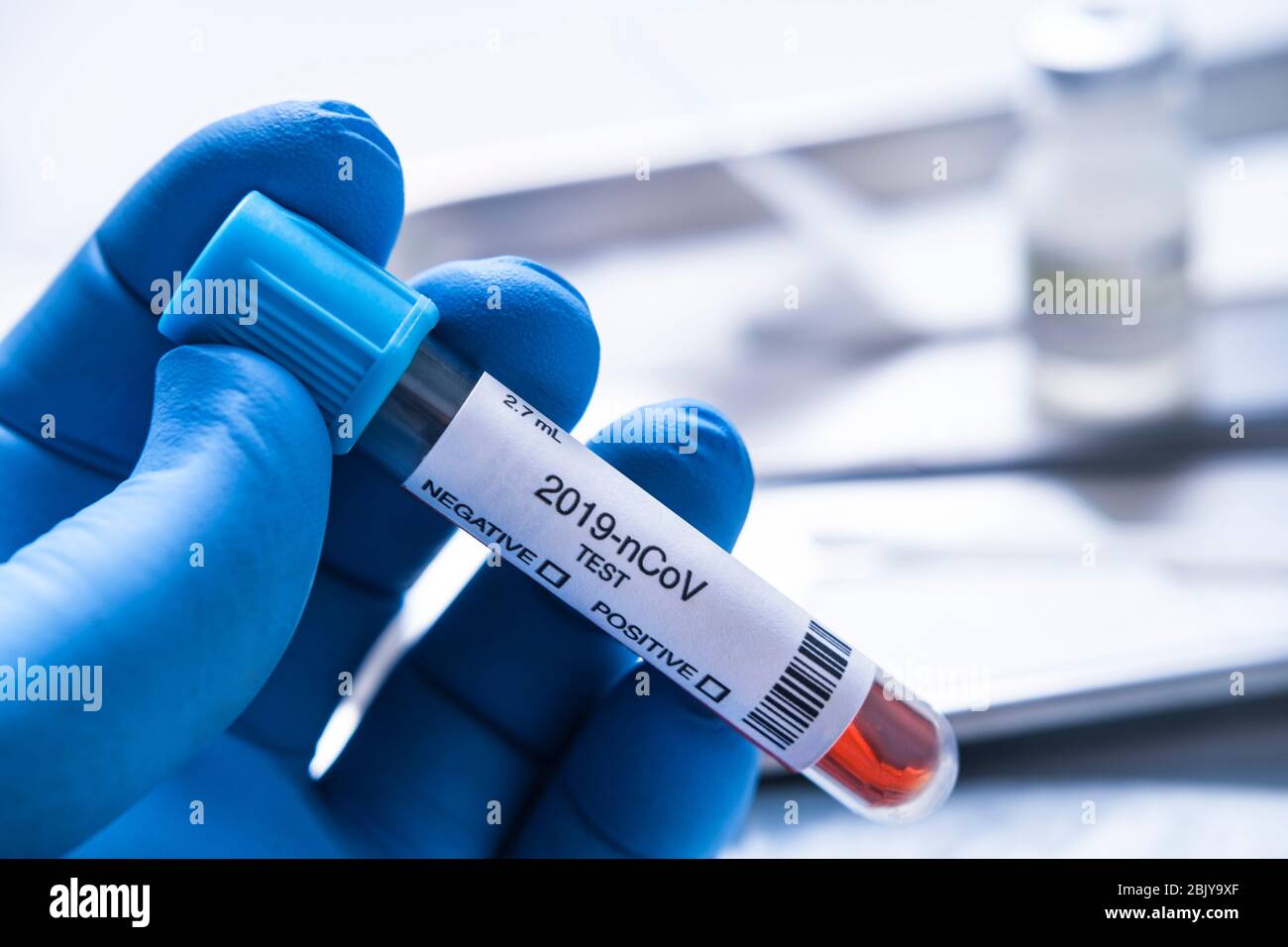 Close-up of gloved hand holding test vial labelled 2019-nCoV Stock ...