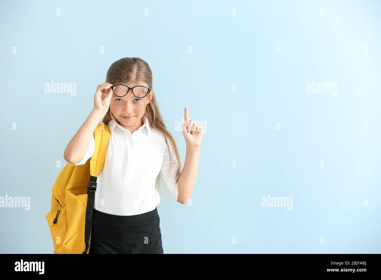 Little schoolgirl with raised index finger on color background Stock ...