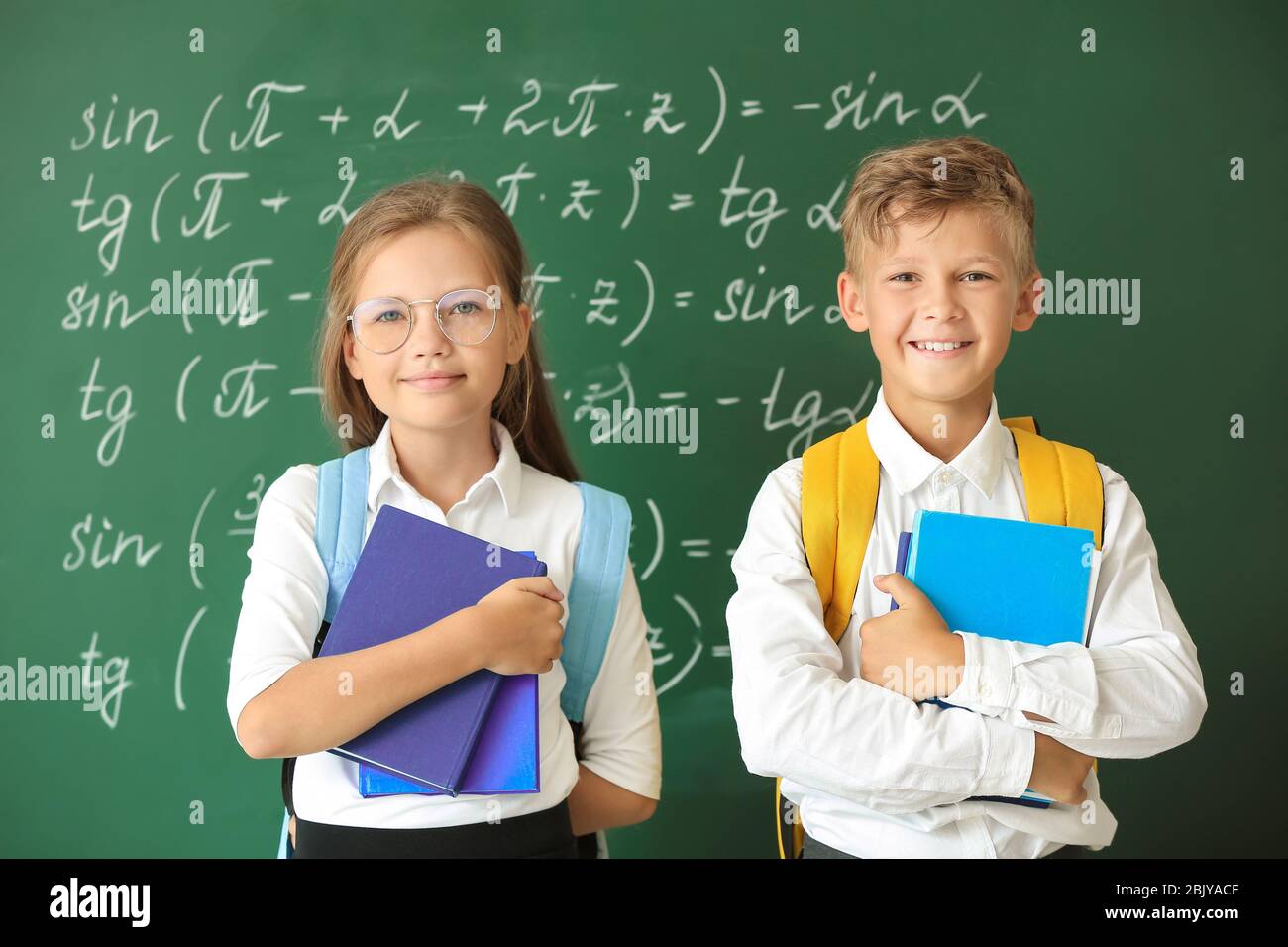 Little pupils near school blackboard in classroom Stock Photo - Alamy