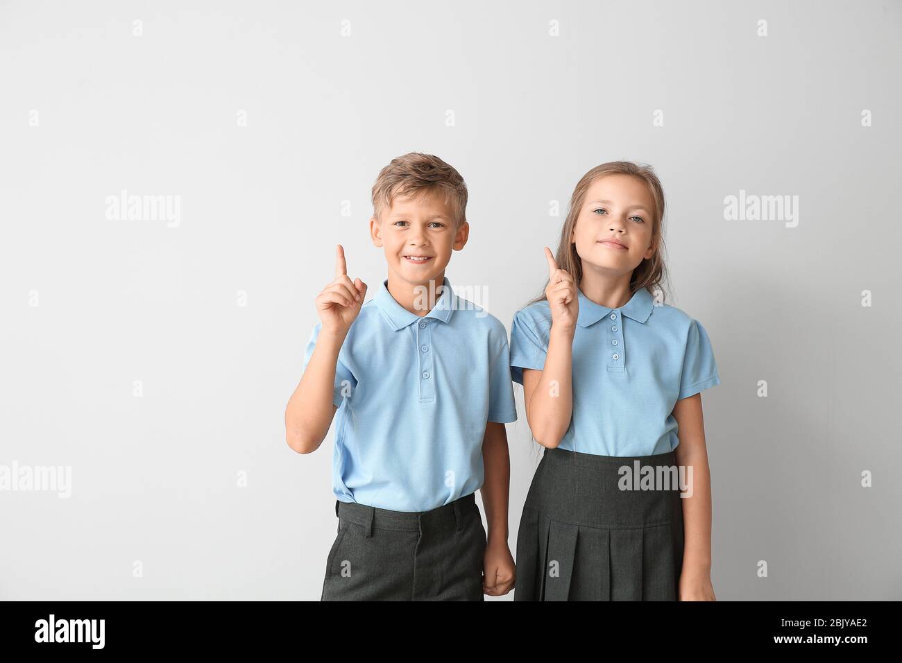 Little pupils with raised index fingers on light background Stock Photo ...