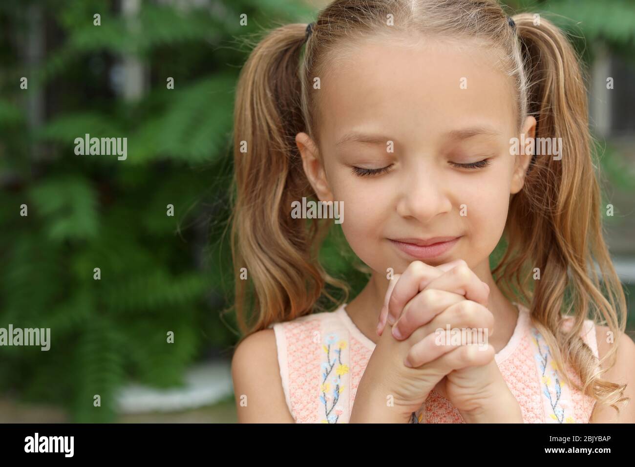 Cute little girl praying outdoors Stock Photo - Alamy