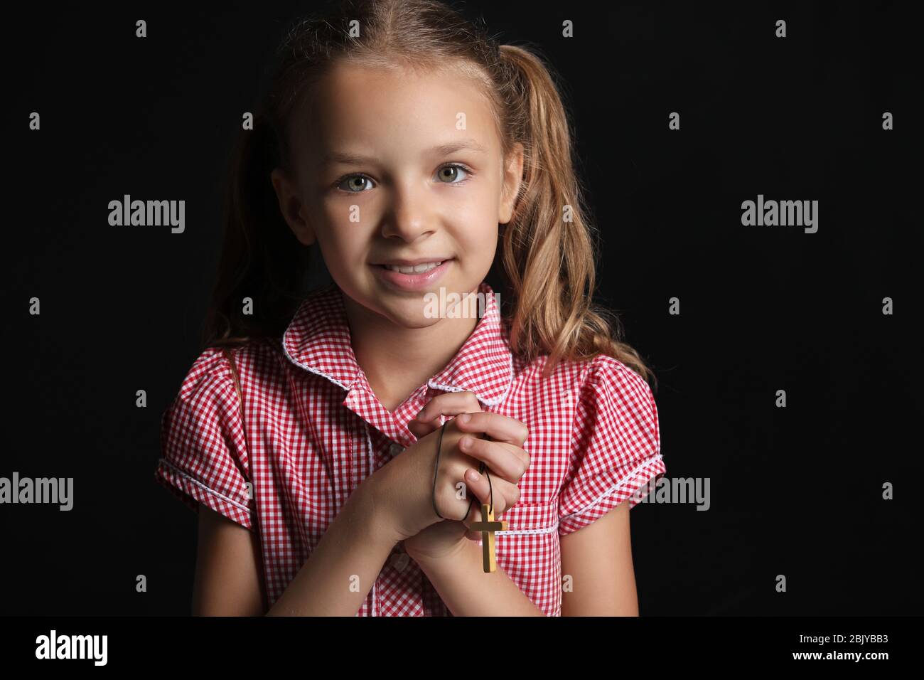 Cute little girl with cross on dark background Stock Photo - Alamy
