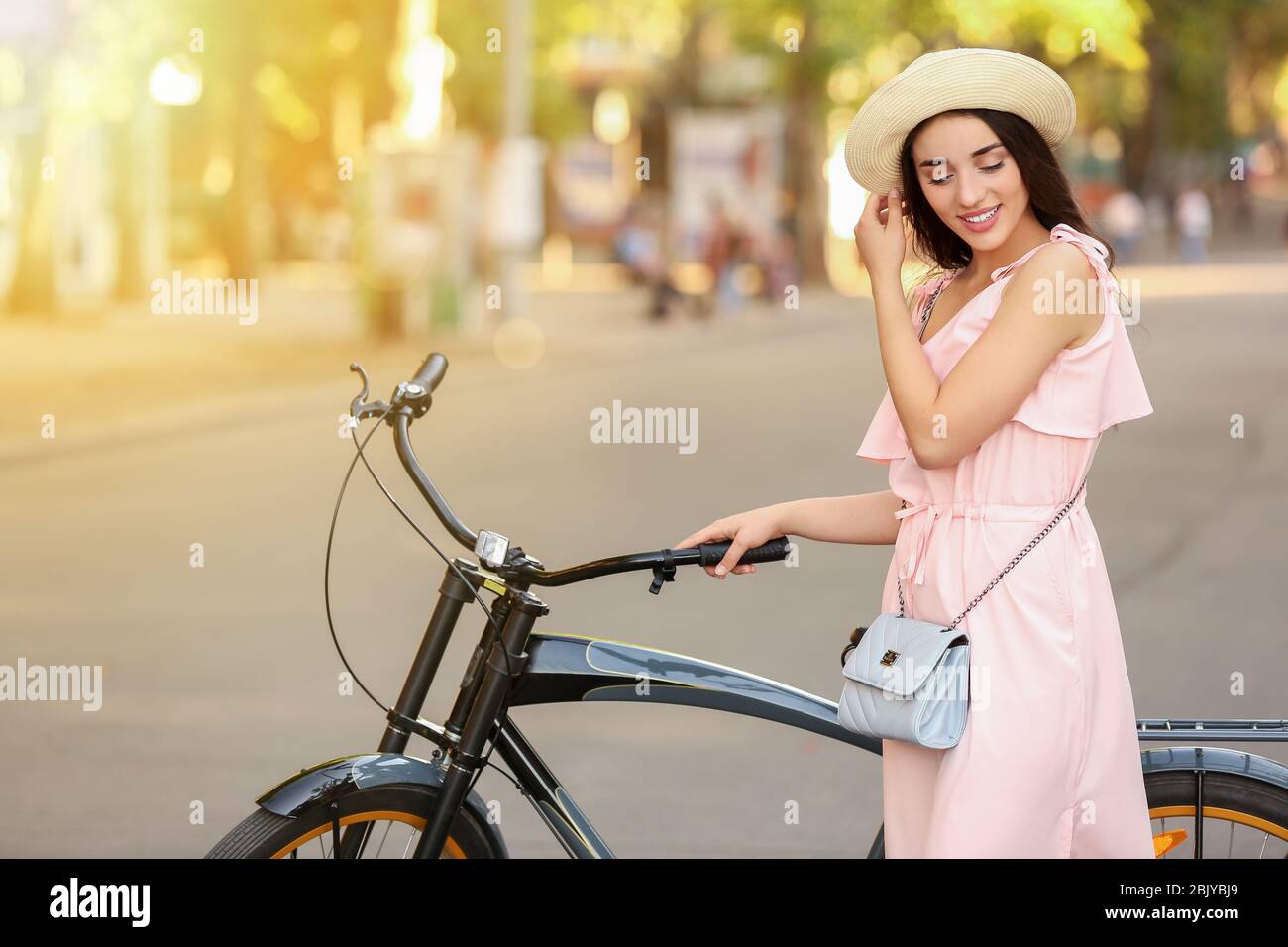 Beautiful young woman with bicycle outdoors Stock Photo - Alamy