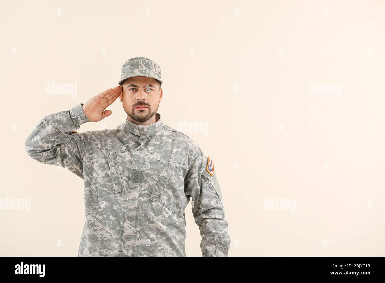 Saluting soldier on light background Stock Photo - Alamy