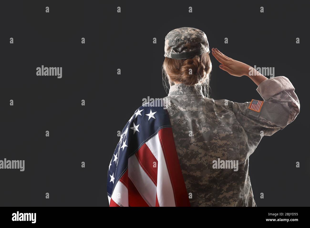 Saluting female soldier with USA flag on dark background, back view ...