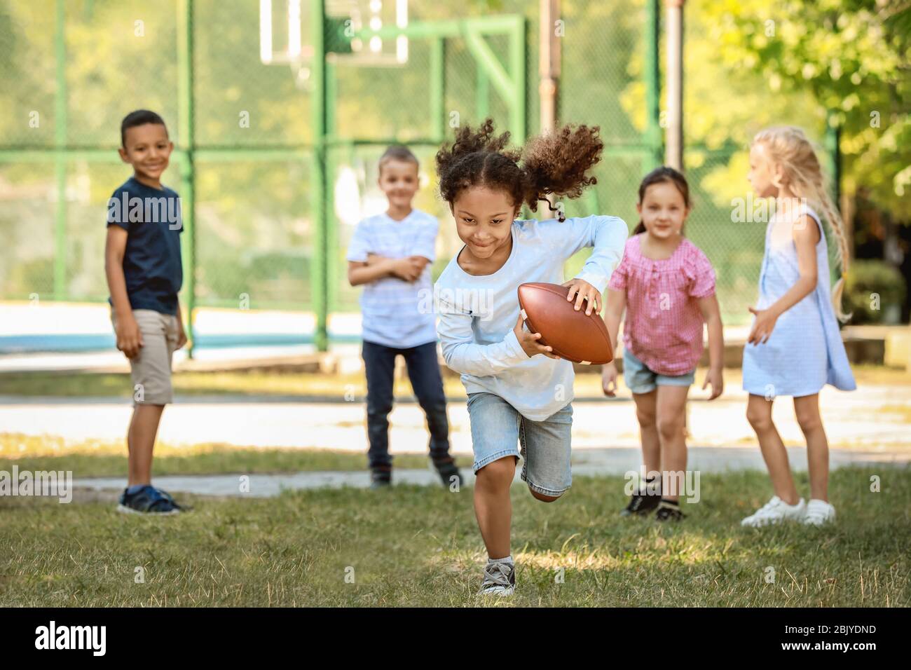 Cute little children playing with rugby ball in park Stock Photo - Alamy