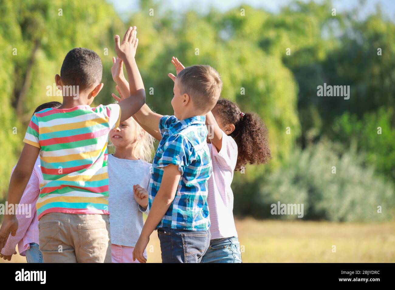 Group of little children giving high-five to each other outdoors Stock ...