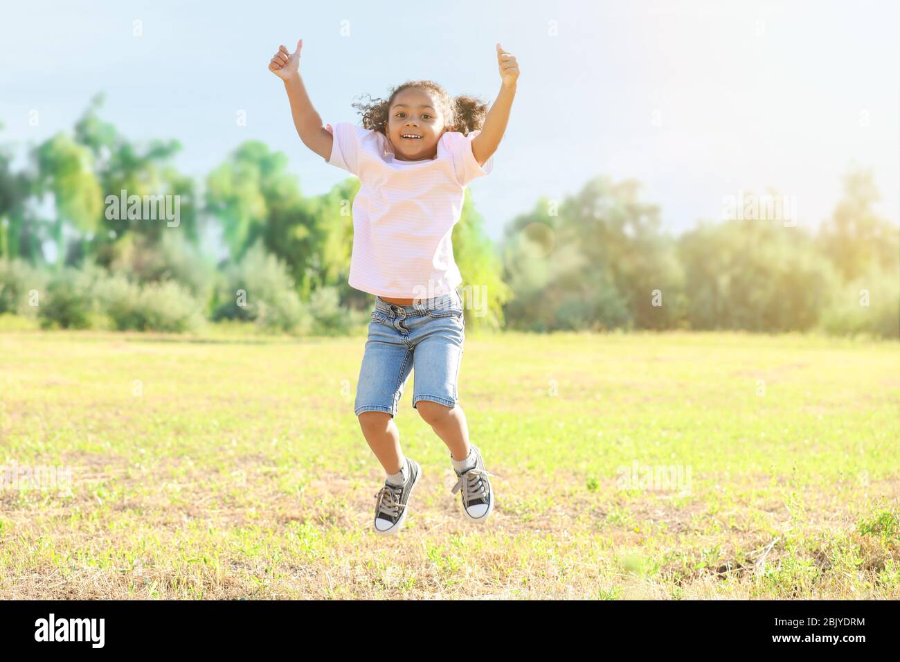 Jumping African-American little girl outdoors Stock Photo - Alamy