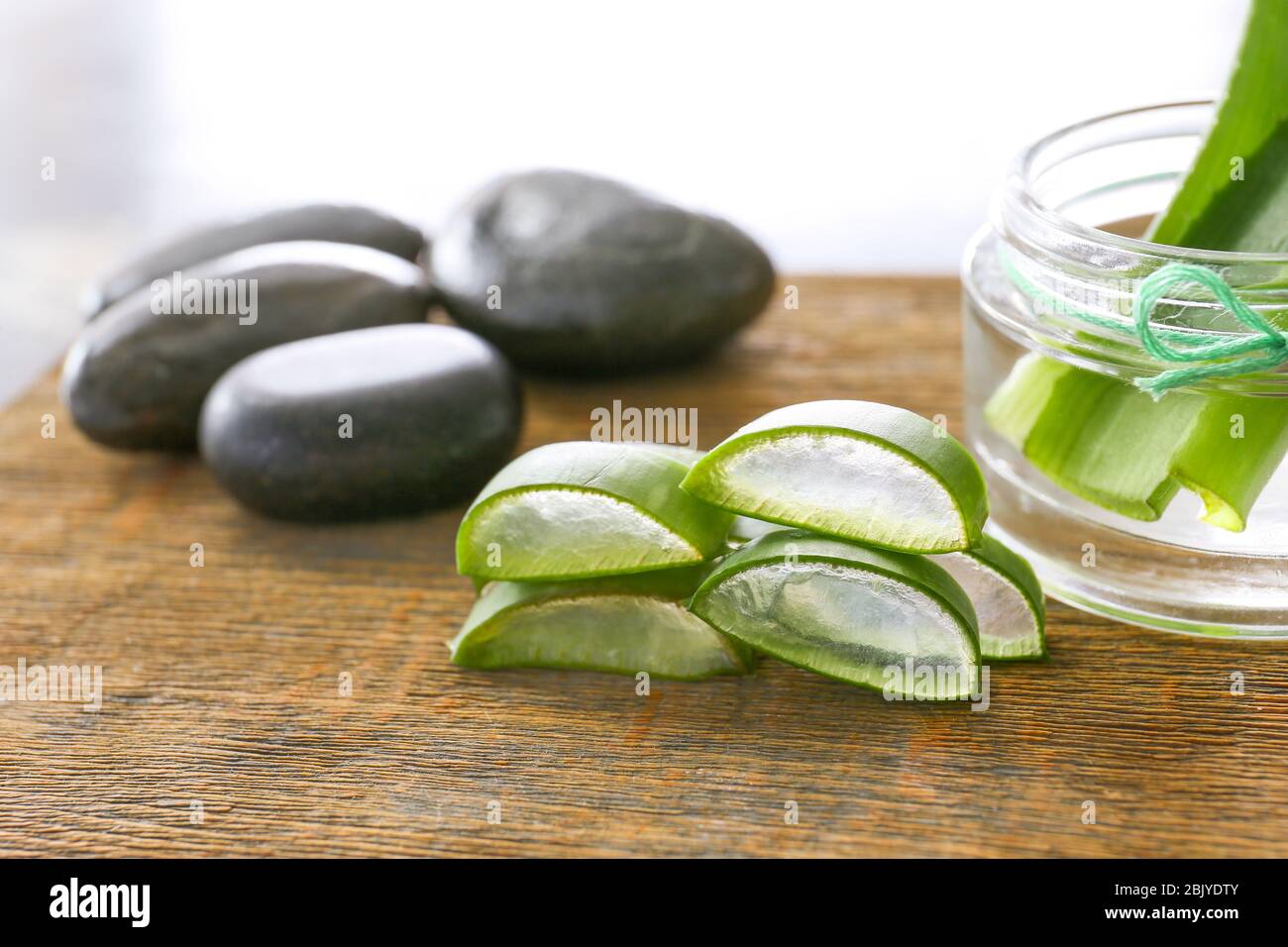 Cut aloe vera and spa stones on wooden table Stock Photo - Alamy