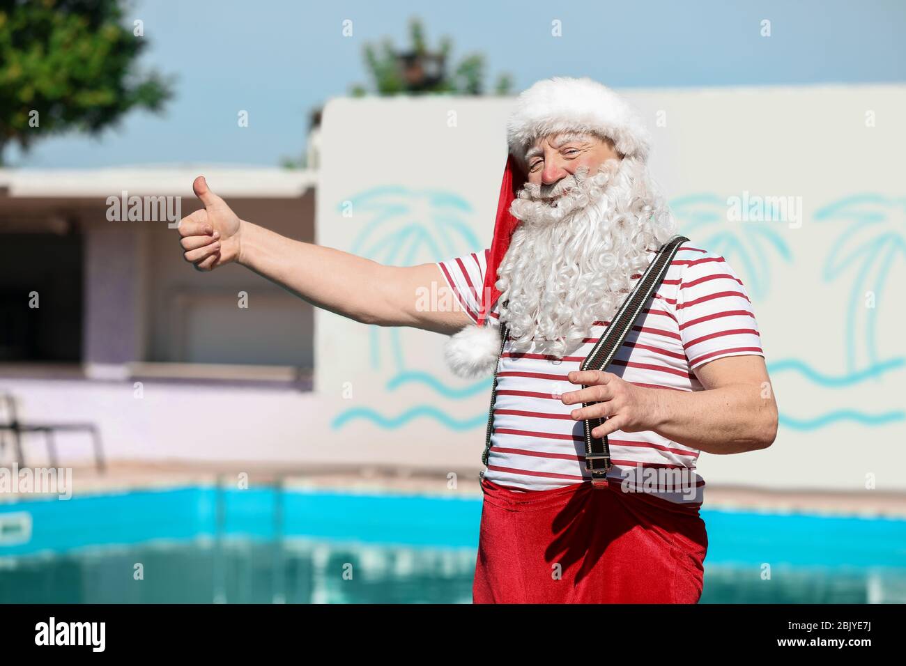 Santa Claus showing thumb-up near swimming pool at resort Stock Photo ...