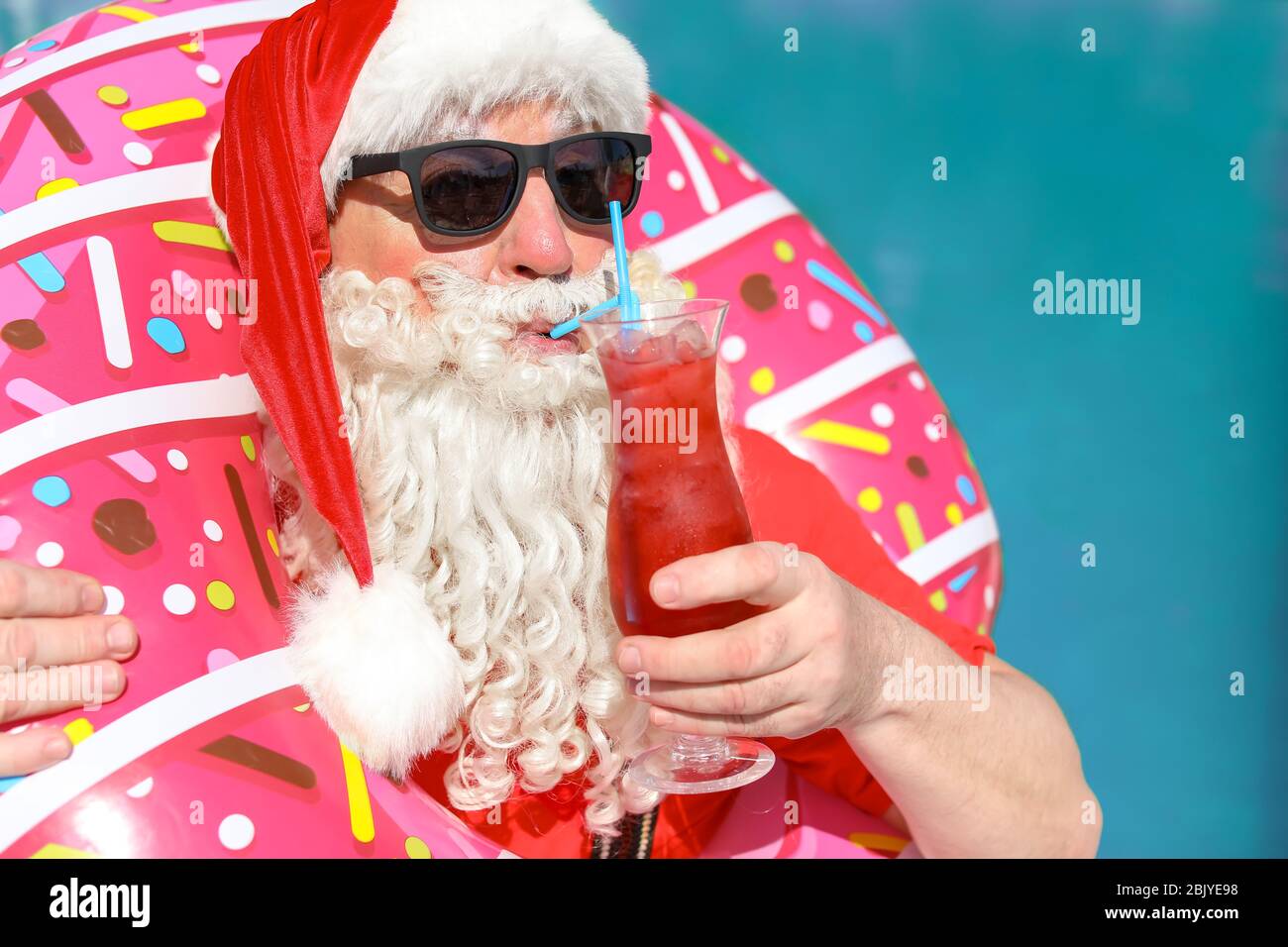 Santa Claus with inflatable ring and cocktail near swimming pool at ...