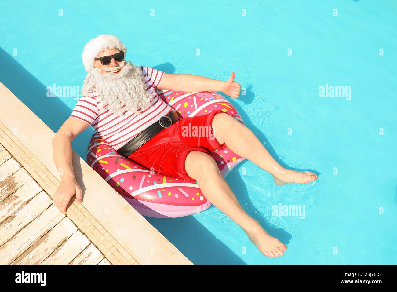 Santa Claus relaxing on inflatable ring in swimming pool Stock Photo ...