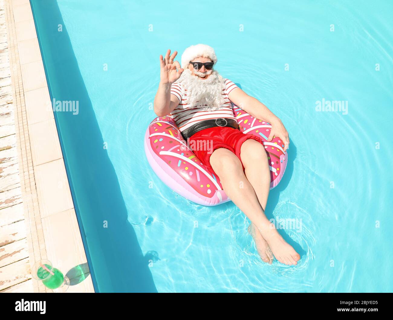 Santa Claus relaxing on inflatable ring in swimming pool Stock Photo ...