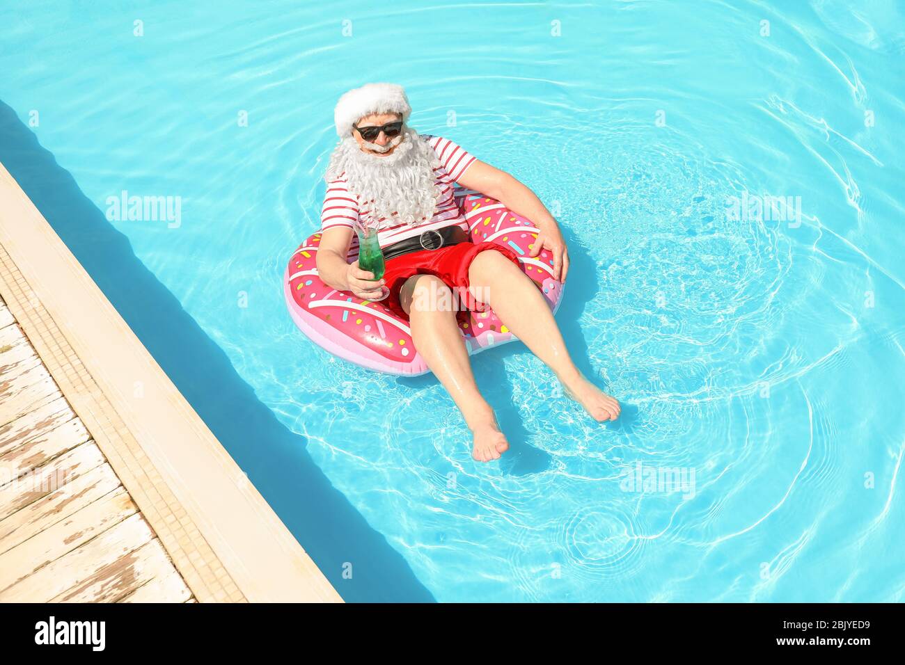Santa Claus relaxing on inflatable ring in swimming pool Stock Photo ...