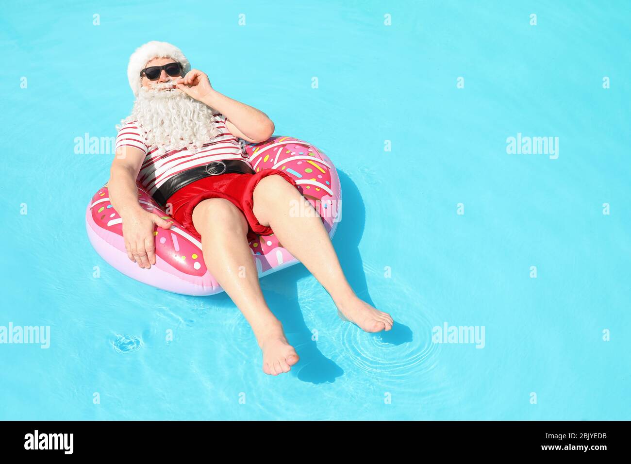 Santa Claus relaxing on inflatable ring in swimming pool Stock Photo ...