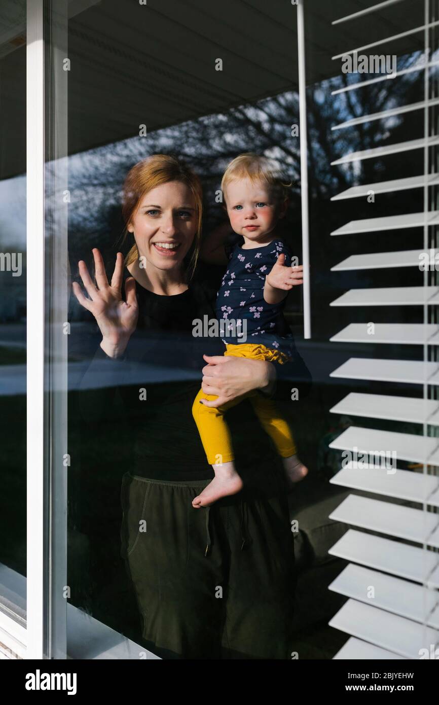 Mother and daughter (2-3) waving through window Stock Photo - Alamy