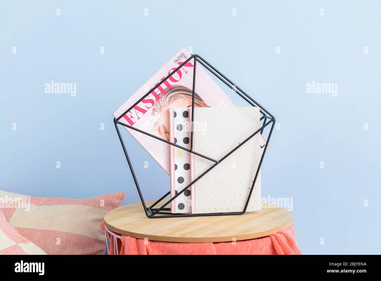Stylish holder with books and magazine on table in room Stock Photo - Alamy