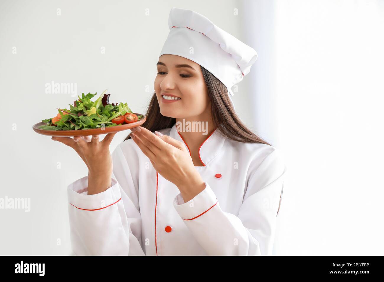 Beautiful female chef with salad in kitchen Stock Photo - Alamy