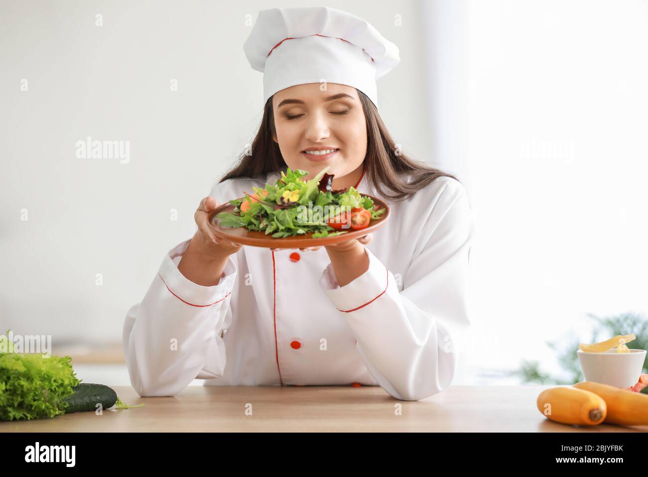 Beautiful female chef with salad in kitchen Stock Photo - Alamy