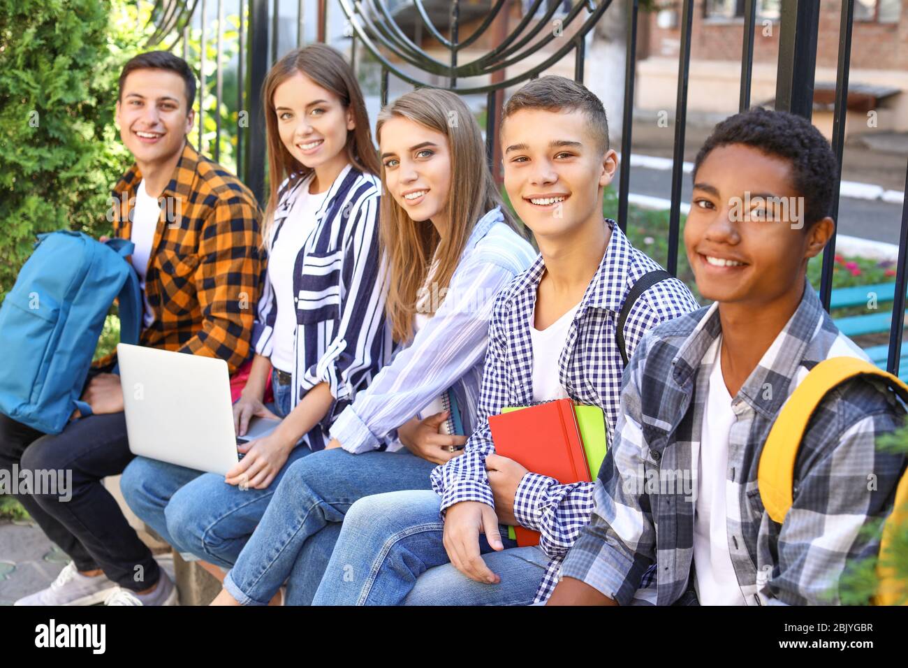 Young students sitting on bench outdoors Stock Photo - Alamy