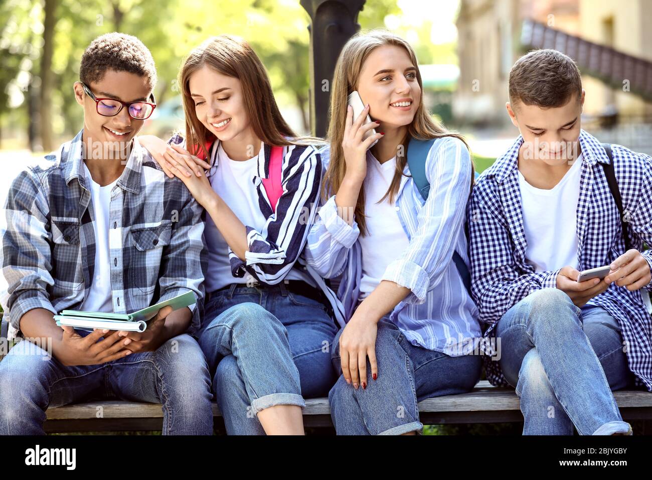 Young students sitting on bench outdoors Stock Photo - Alamy