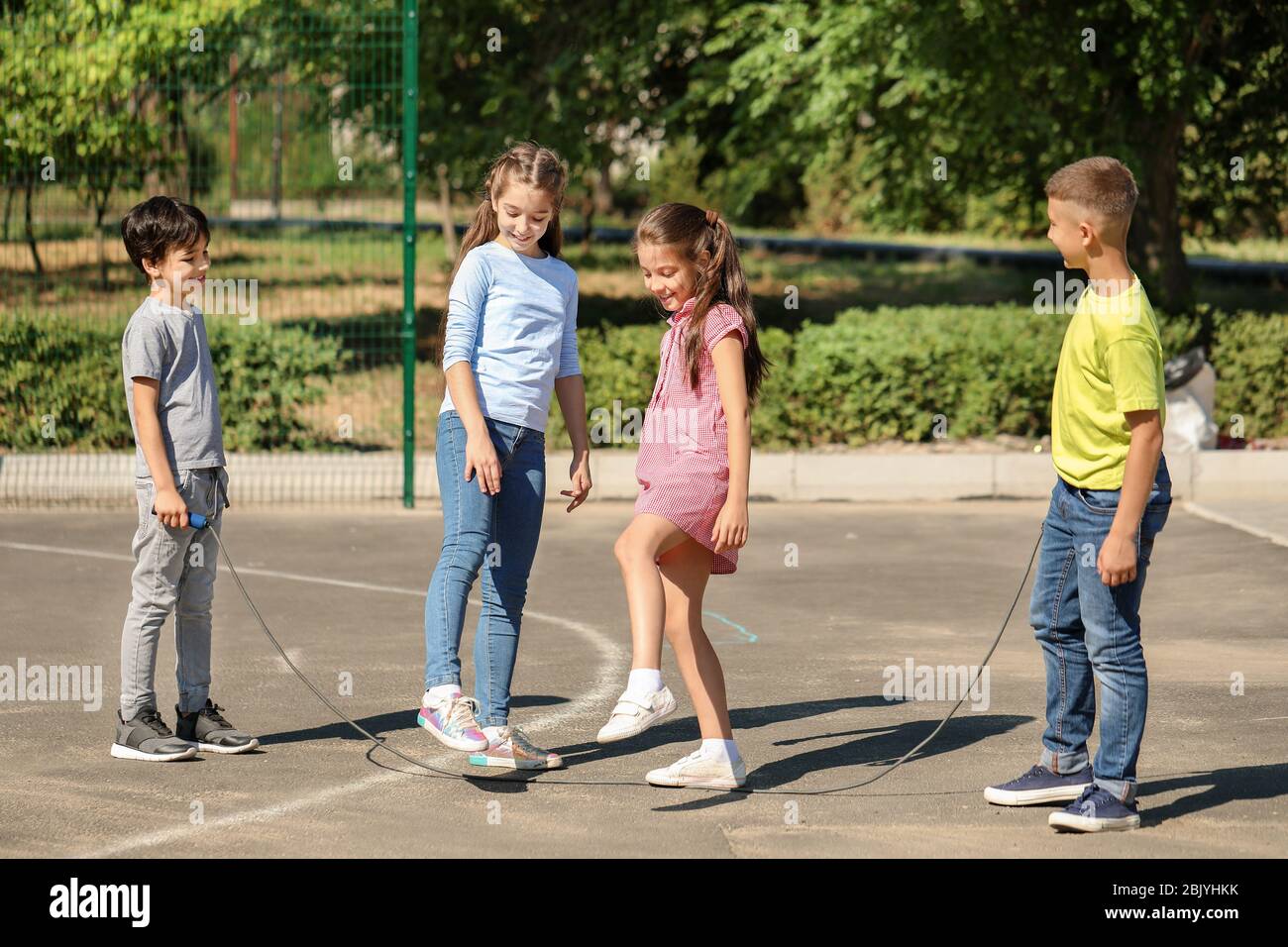 Cute little children jumping rope on playground Stock Photo - Alamy