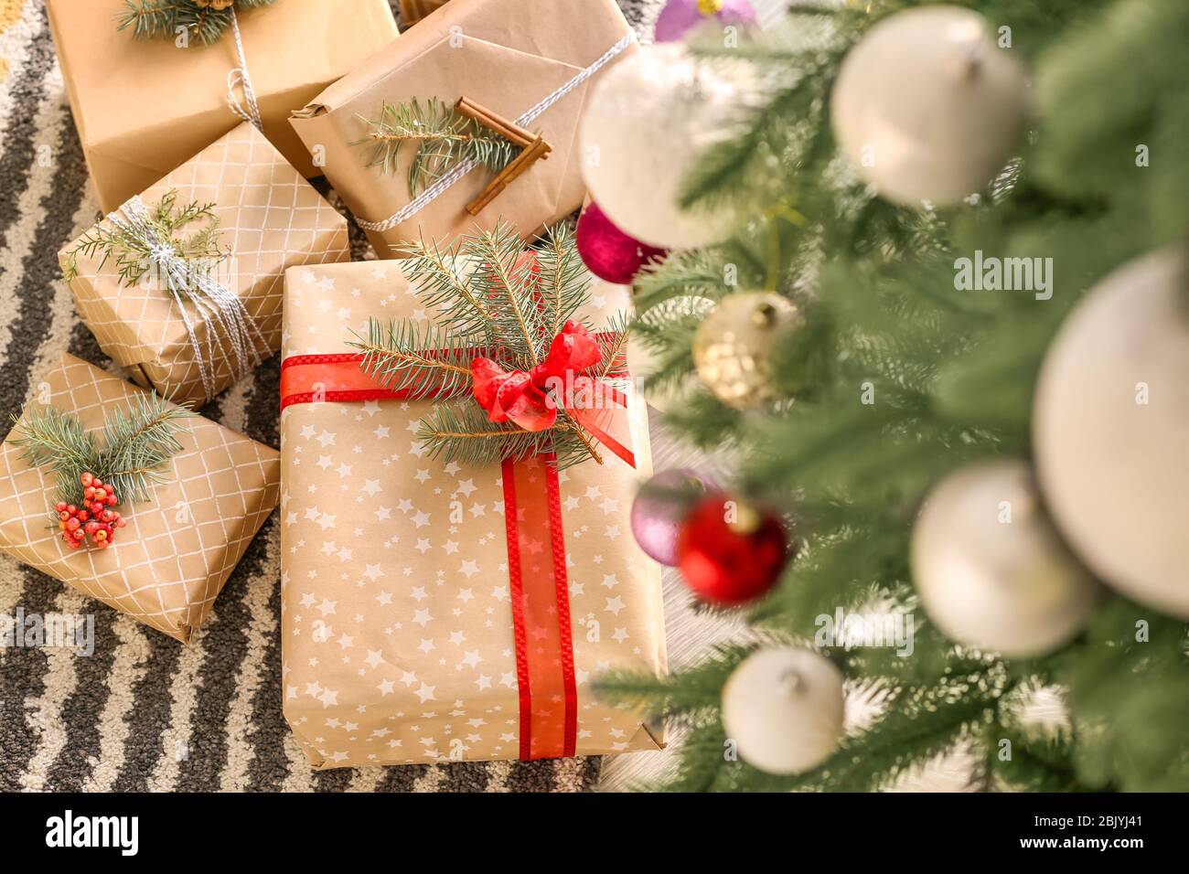 Beautiful gift boxes under fir tree in room Stock Photo - Alamy