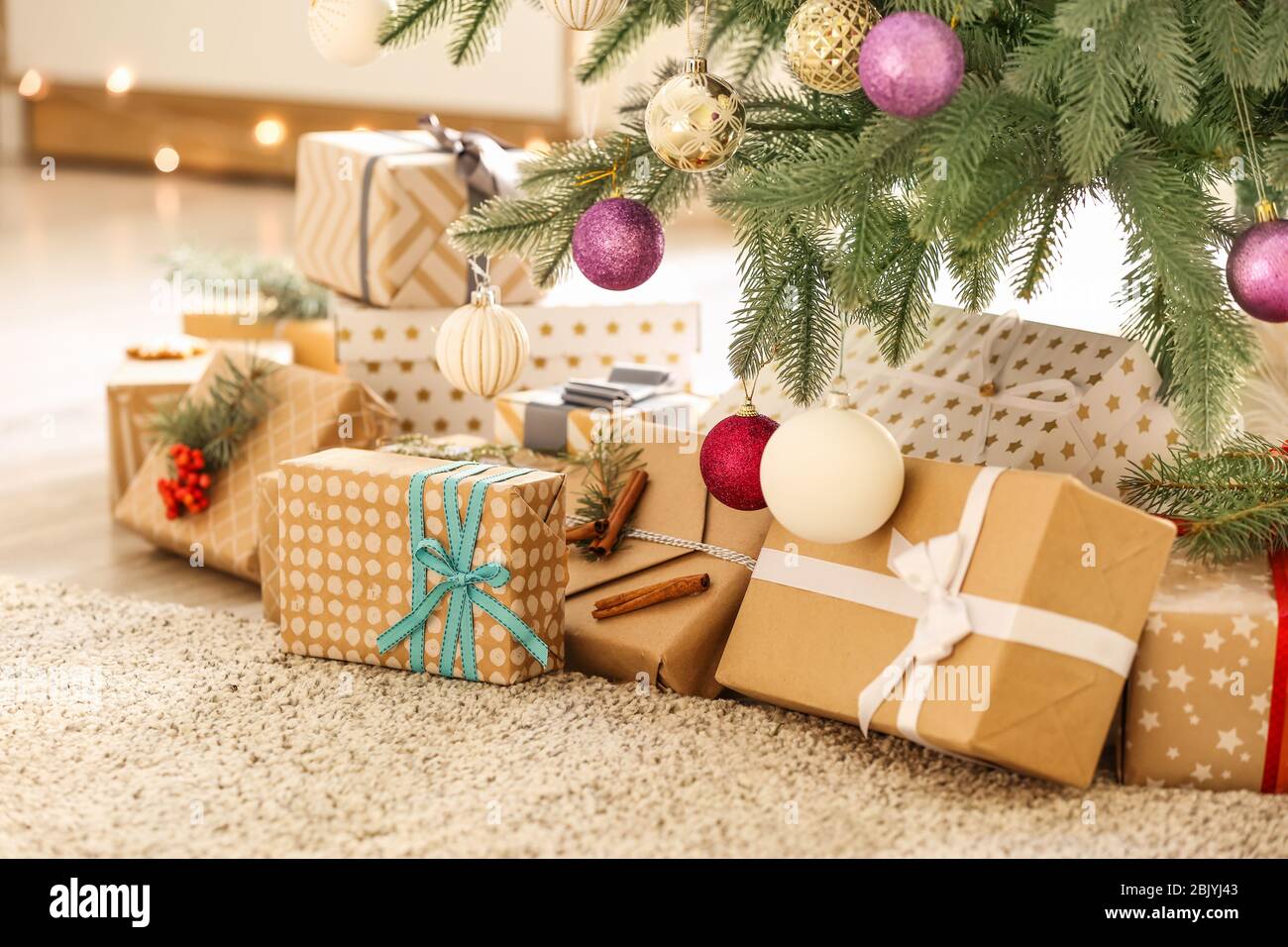 Beautiful gift boxes under fir tree in room Stock Photo - Alamy