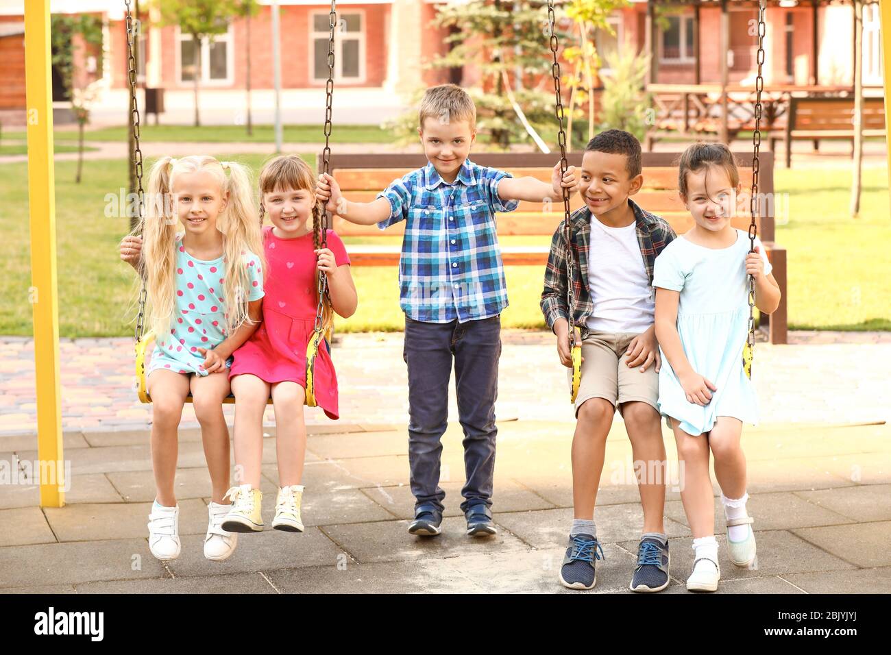 Cute little children on swings in park Stock Photo - Alamy