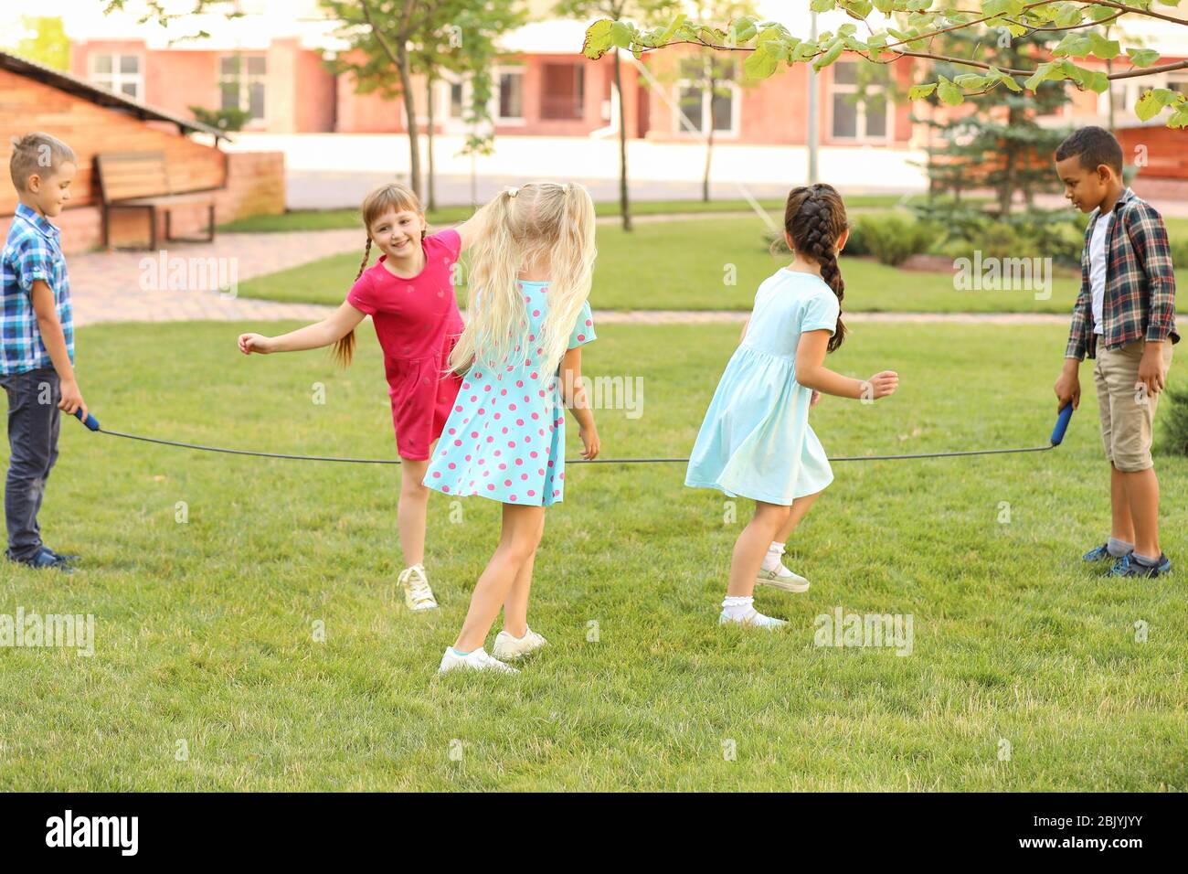Cute little children jumping rope in park Stock Photo - Alamy