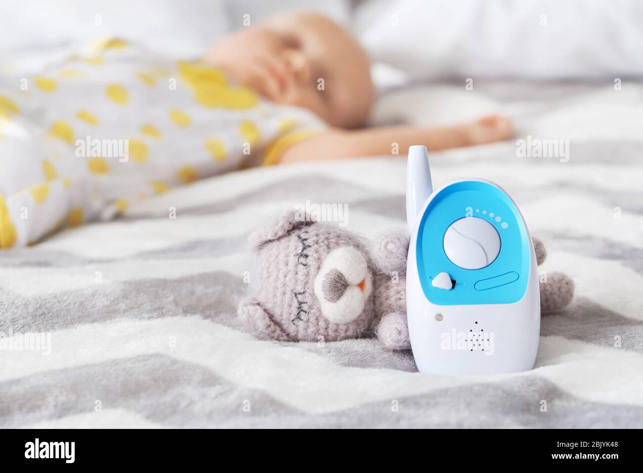 Modern baby monitor and toy on bed of sleeping infant Stock Photo - Alamy