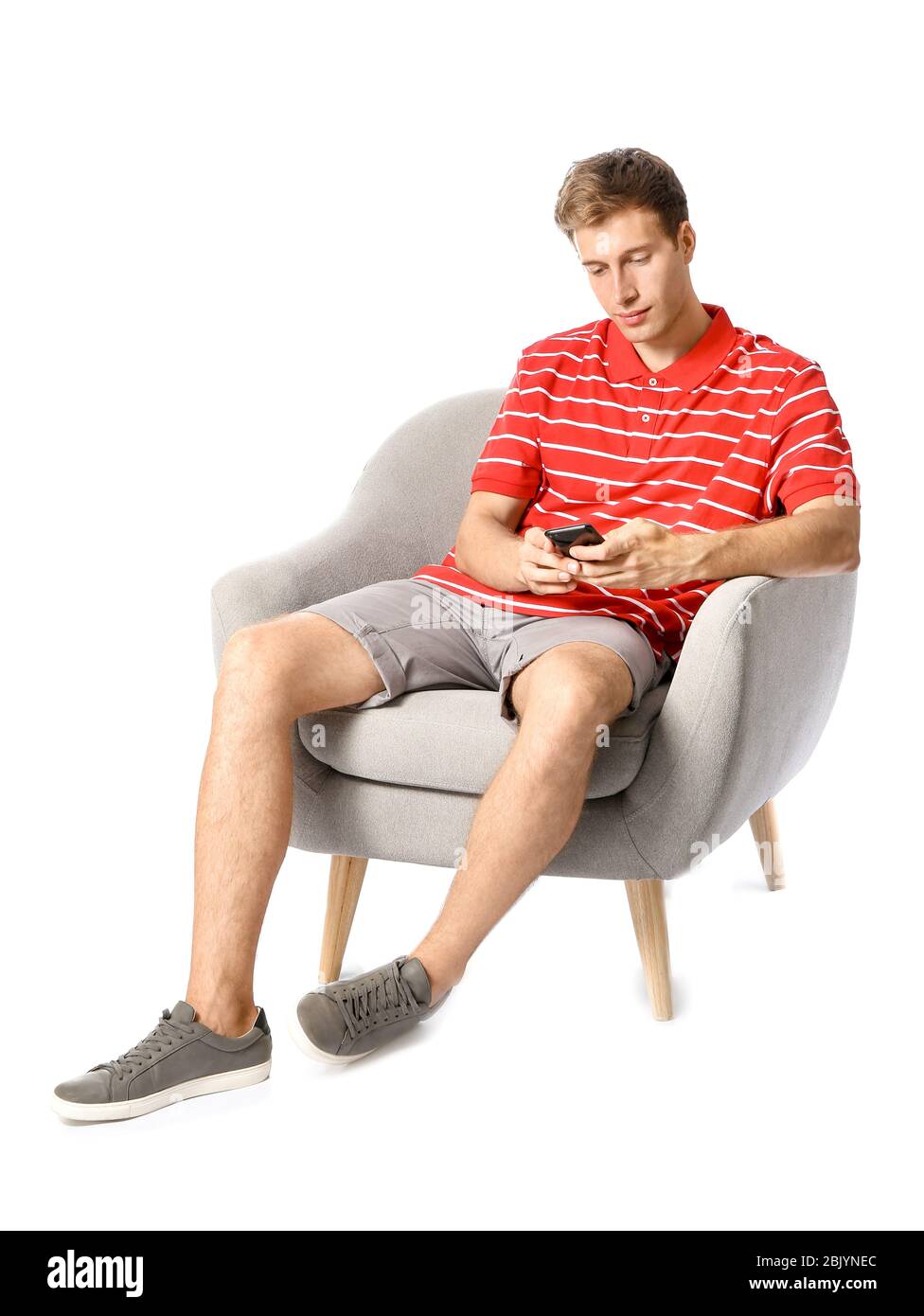 Young man with mobile phone relaxing in armchair against white ...