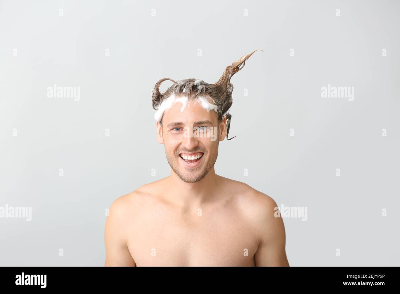 Funny young man washing hair against grey background Stock Photo - Alamy