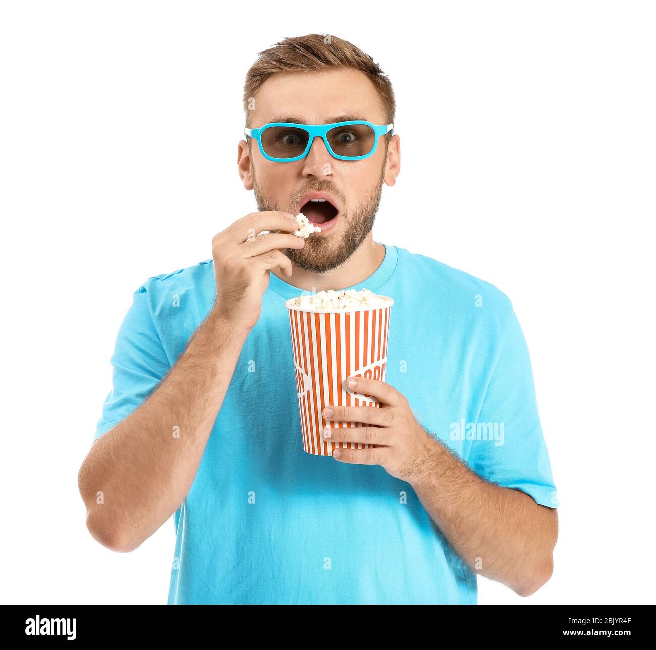 Young man with popcorn watching horror movie on white background Stock ...