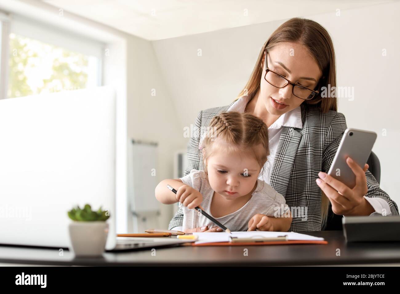Working mother with her daughter in office Stock Photo - Alamy