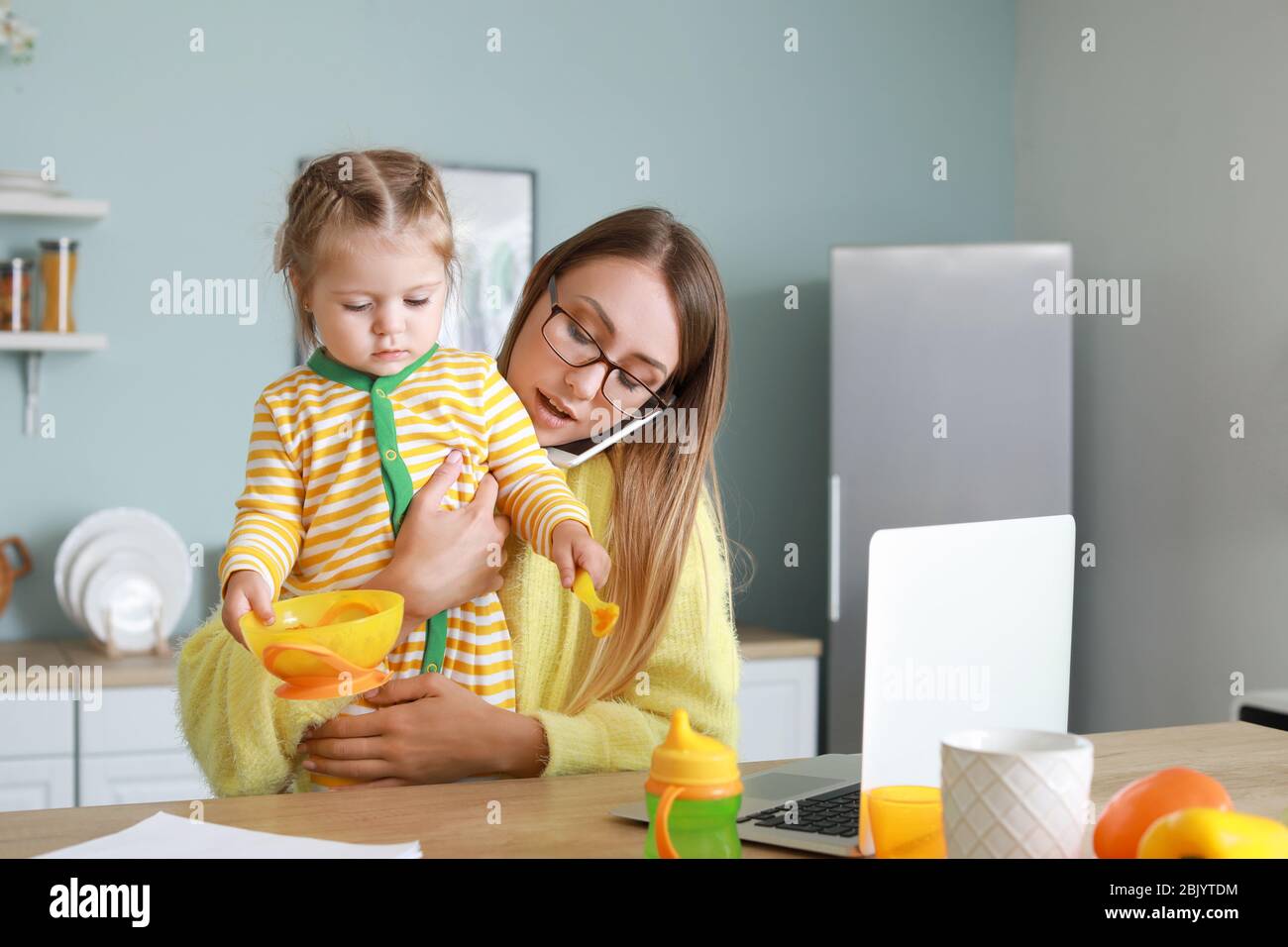 Working mother with her daughter in kitchen at home Stock Photo - Alamy