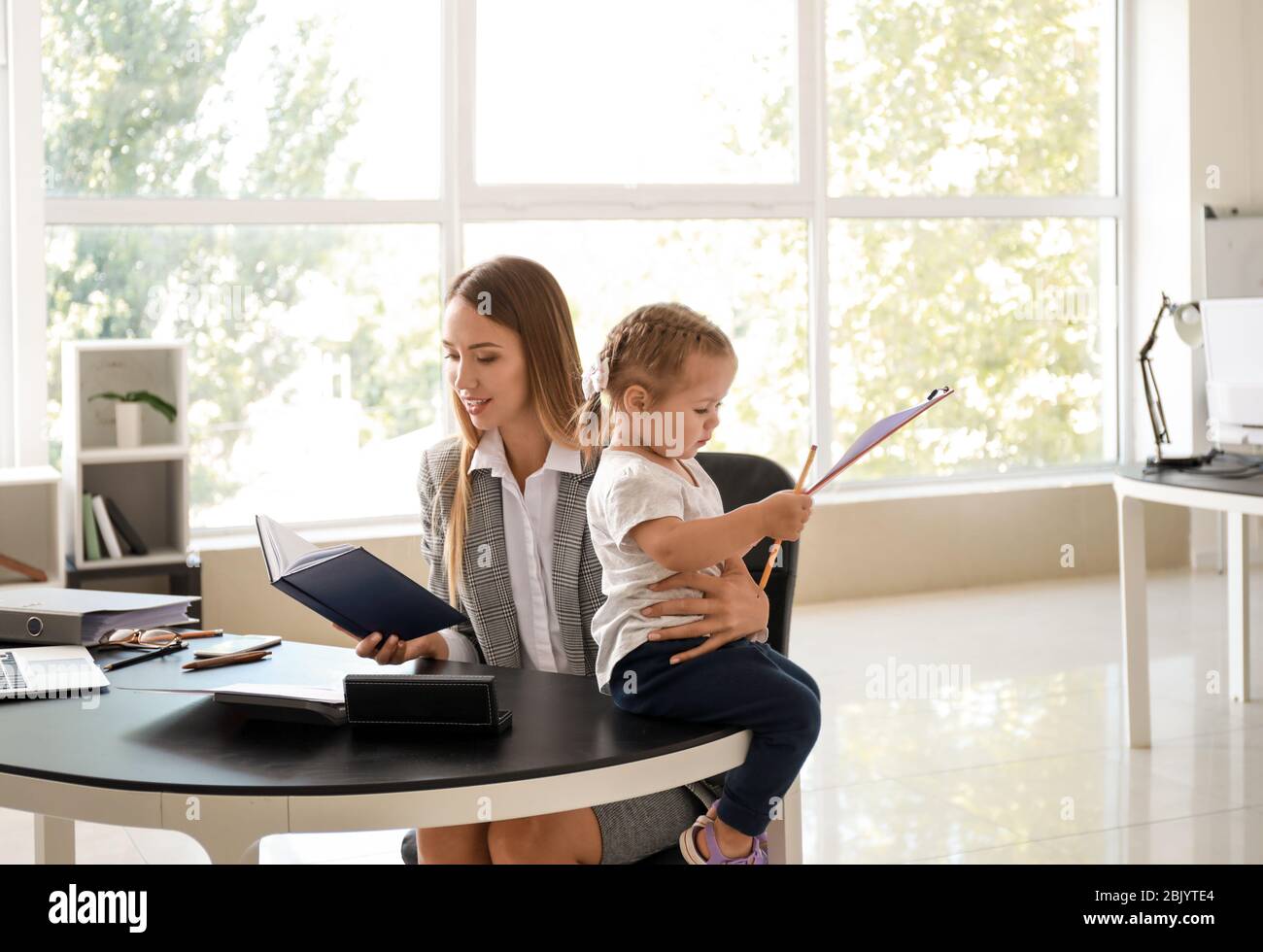 Working mother with her daughter in office Stock Photo - Alamy