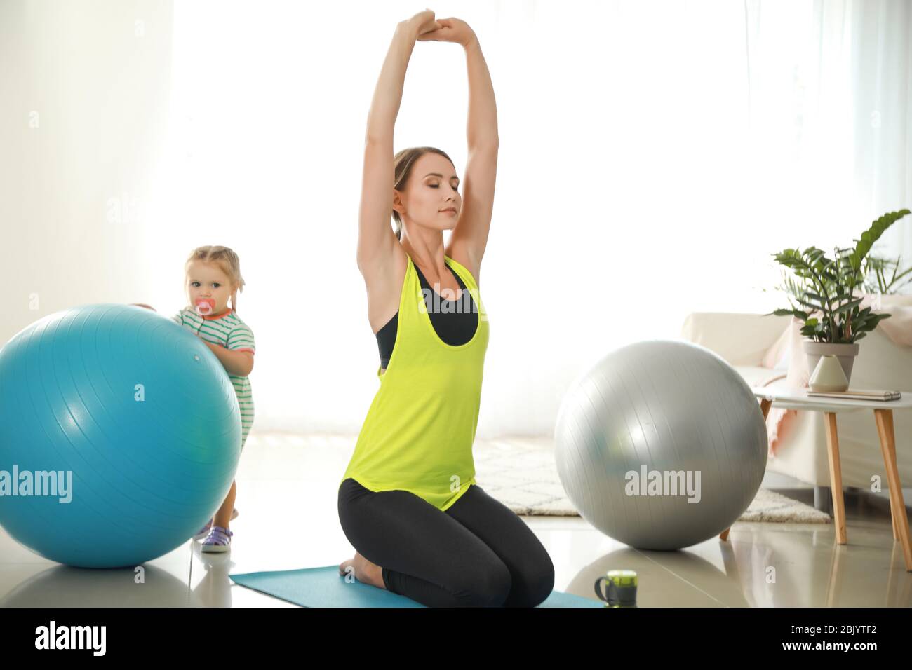 Sporty mother with little daughter training at home Stock Photo - Alamy