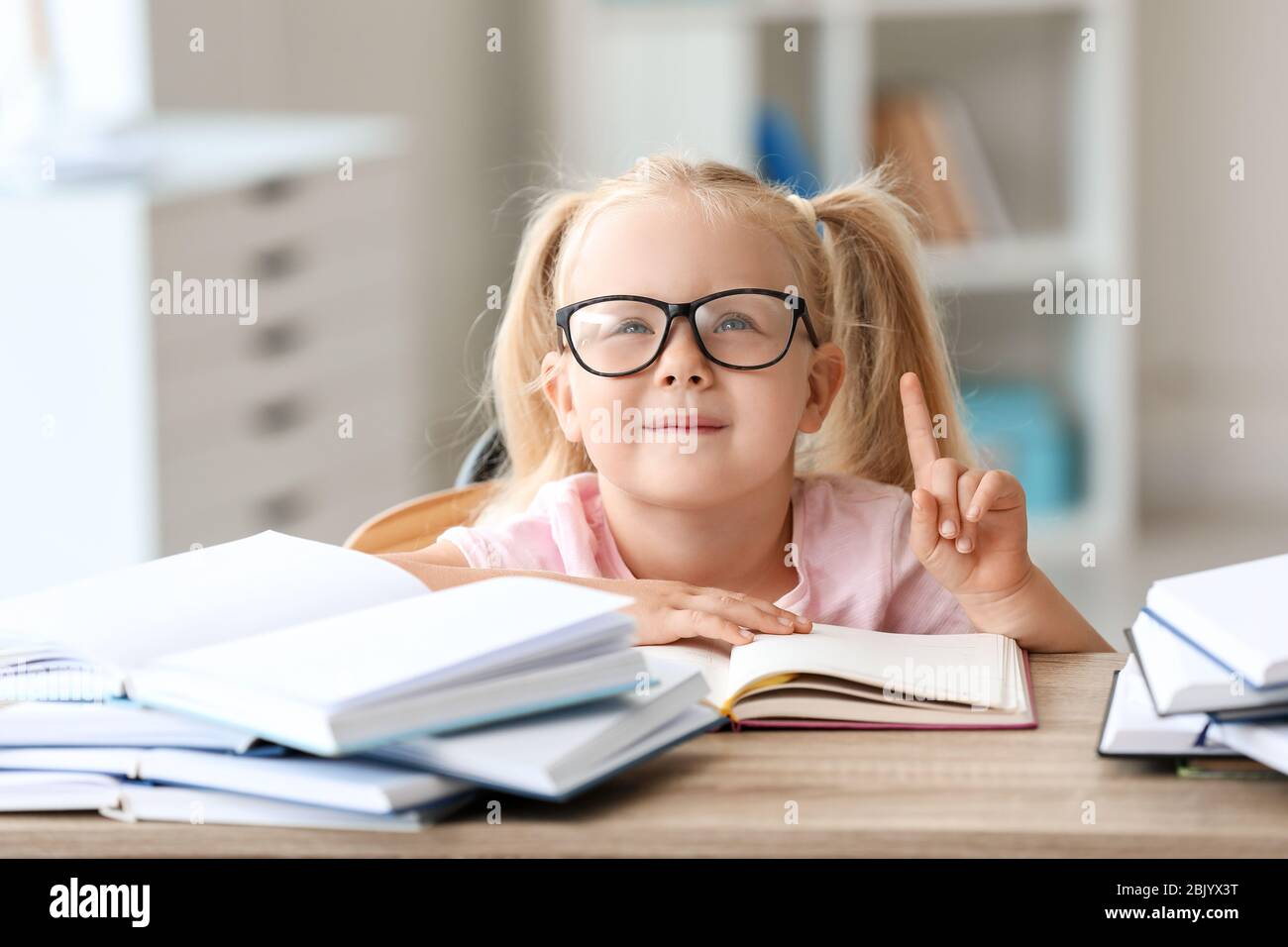 Smart little schoolgirl with raised index finger in classroom Stock ...