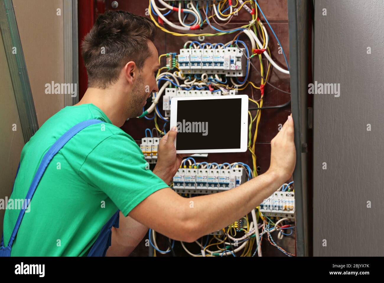 Electrician with tablet computer installing alarm system in ...