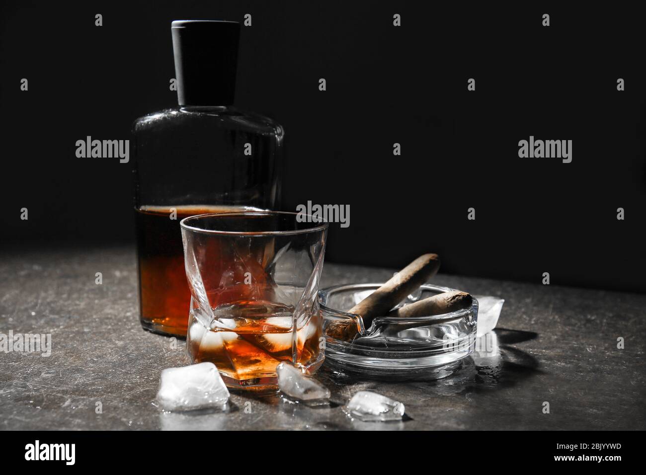 Glass and bottle of cold whiskey with ice and cigar on dark table Stock ...