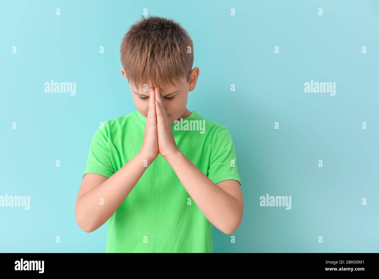 Praying little boy on color background Stock Photo - Alamy